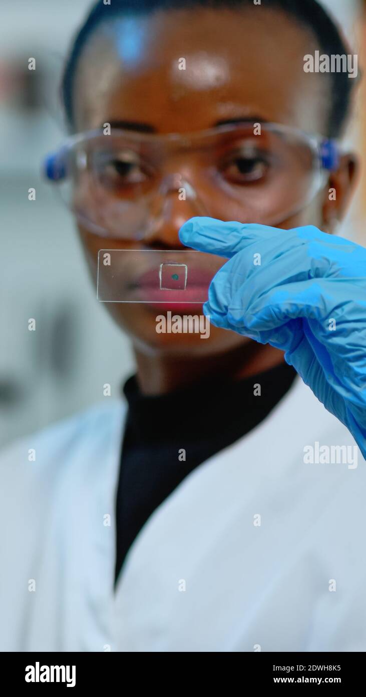 Black technician doing experiment in modern equipped lab looking at ...
