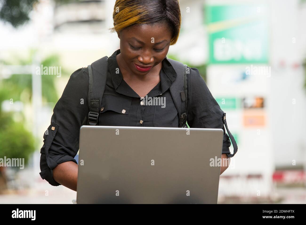 student sitting with backpack looking at laptop smiling Stock Photo - Alamy