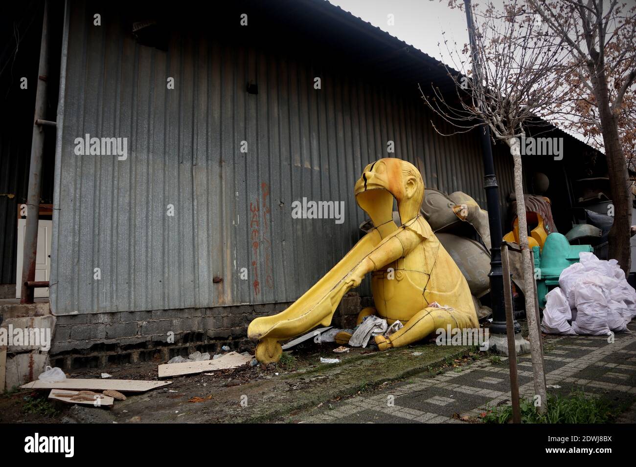 An old, yellow and broken plastic slide from a playground ekes out a ...
