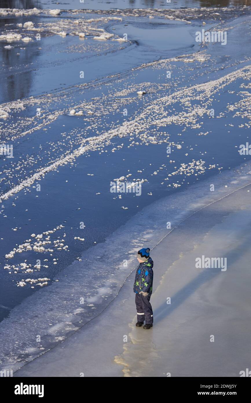 A little boy stands on an icy river Stock Photo - Alamy