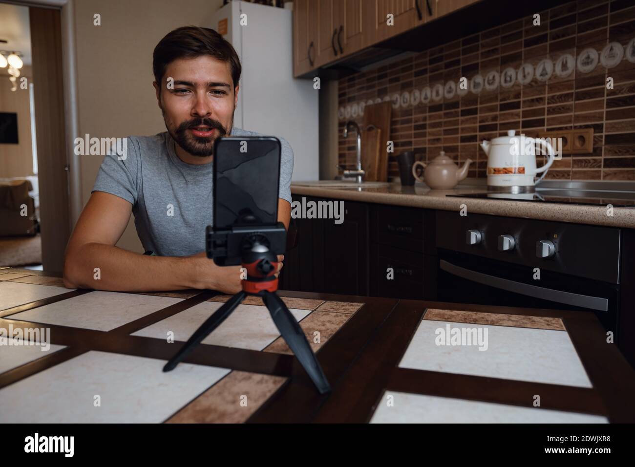 Young man having video call via smartphone in the home office. Virtual ...
