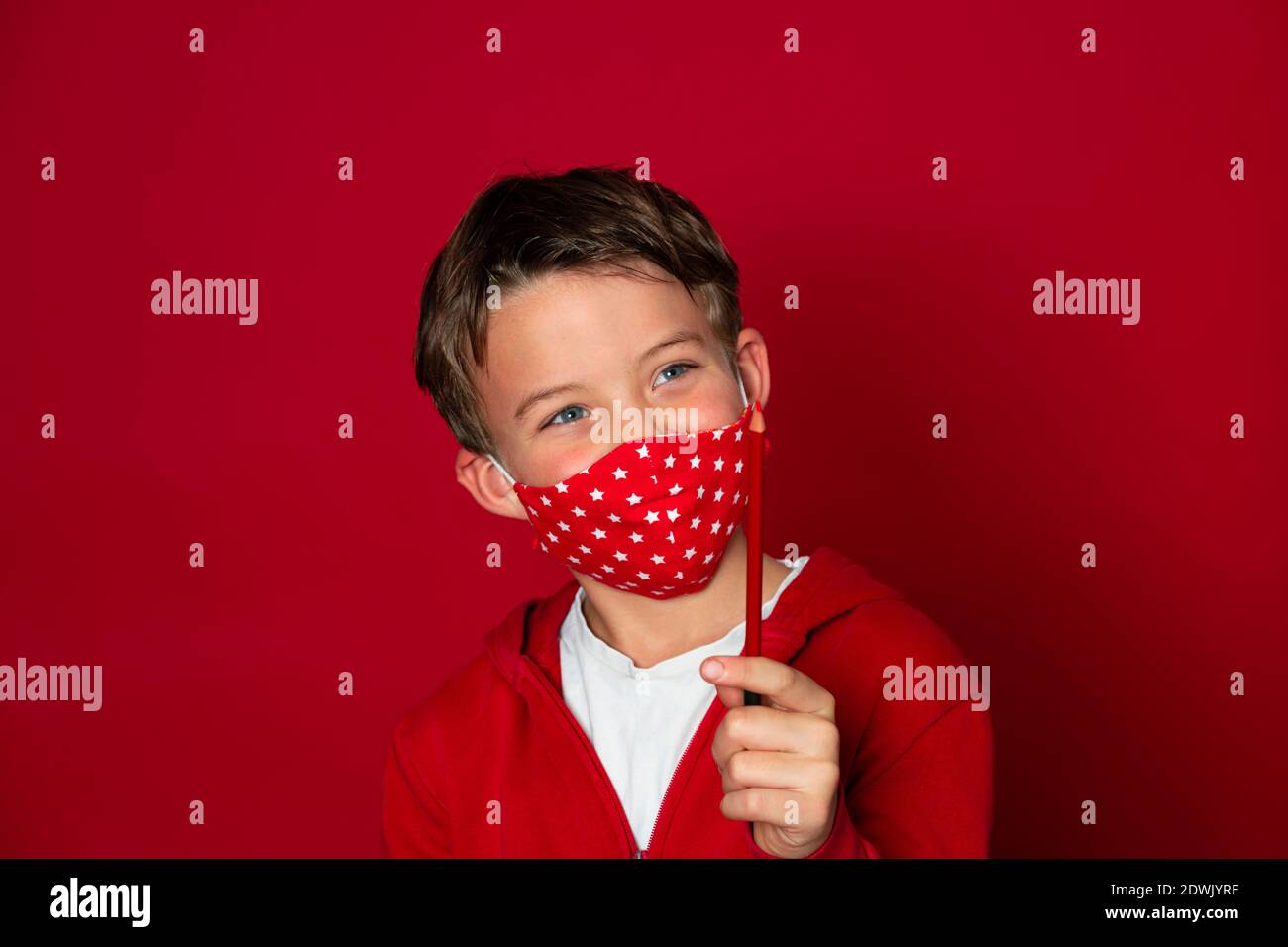 cool young boy with red mask and red pencil in front of red background ...