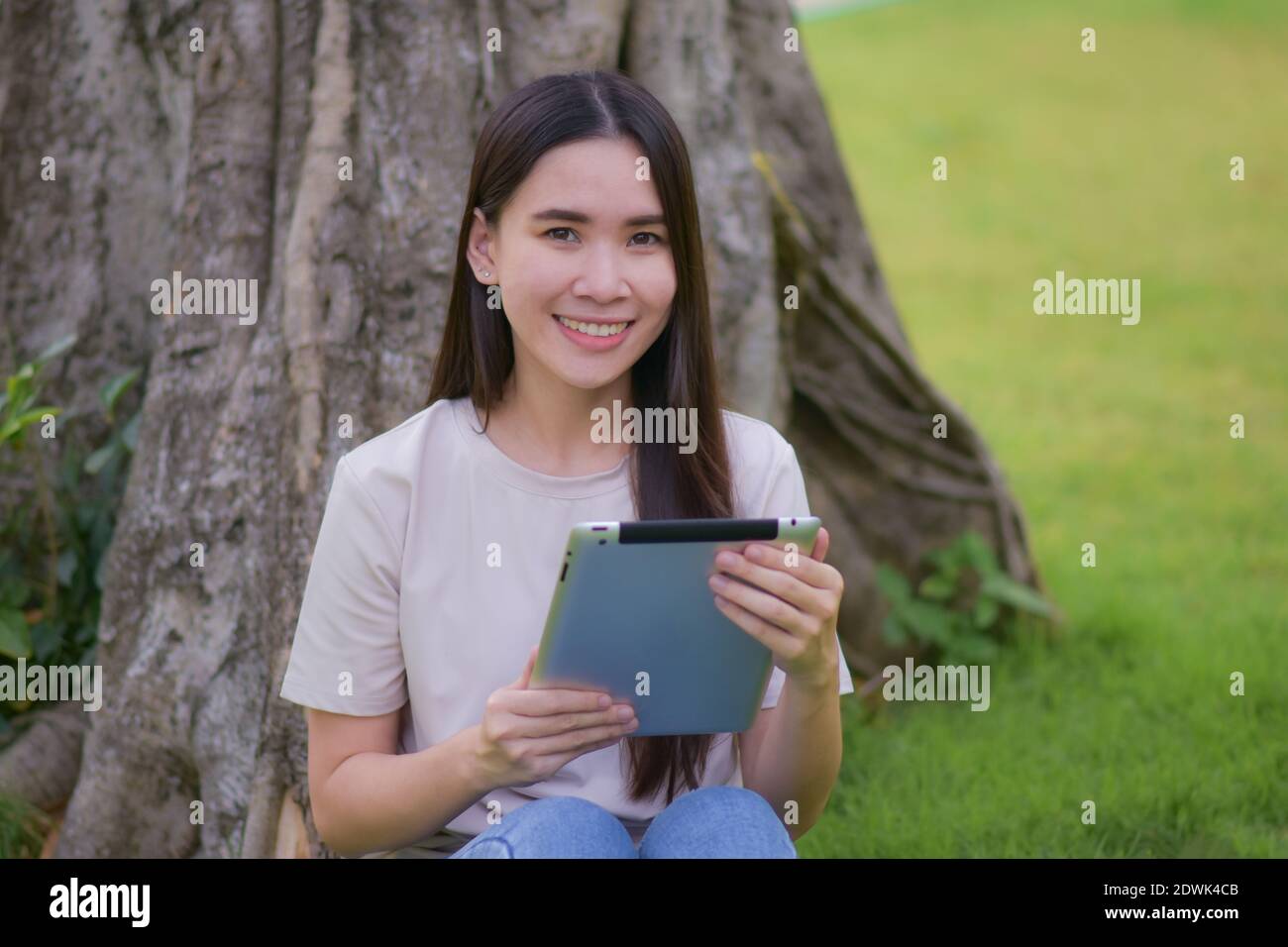 Beauty women using tablet reading E-book sitting in city park morning ...