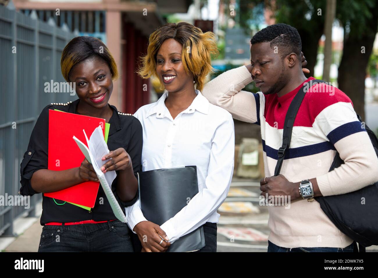 group of students standing outside after class with notebook smiling ...
