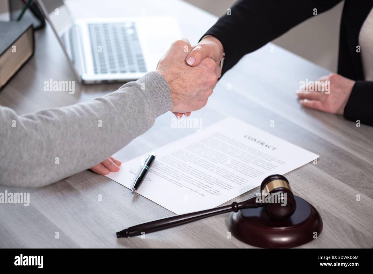 Handshake between female lawyer and male client after signing a ...