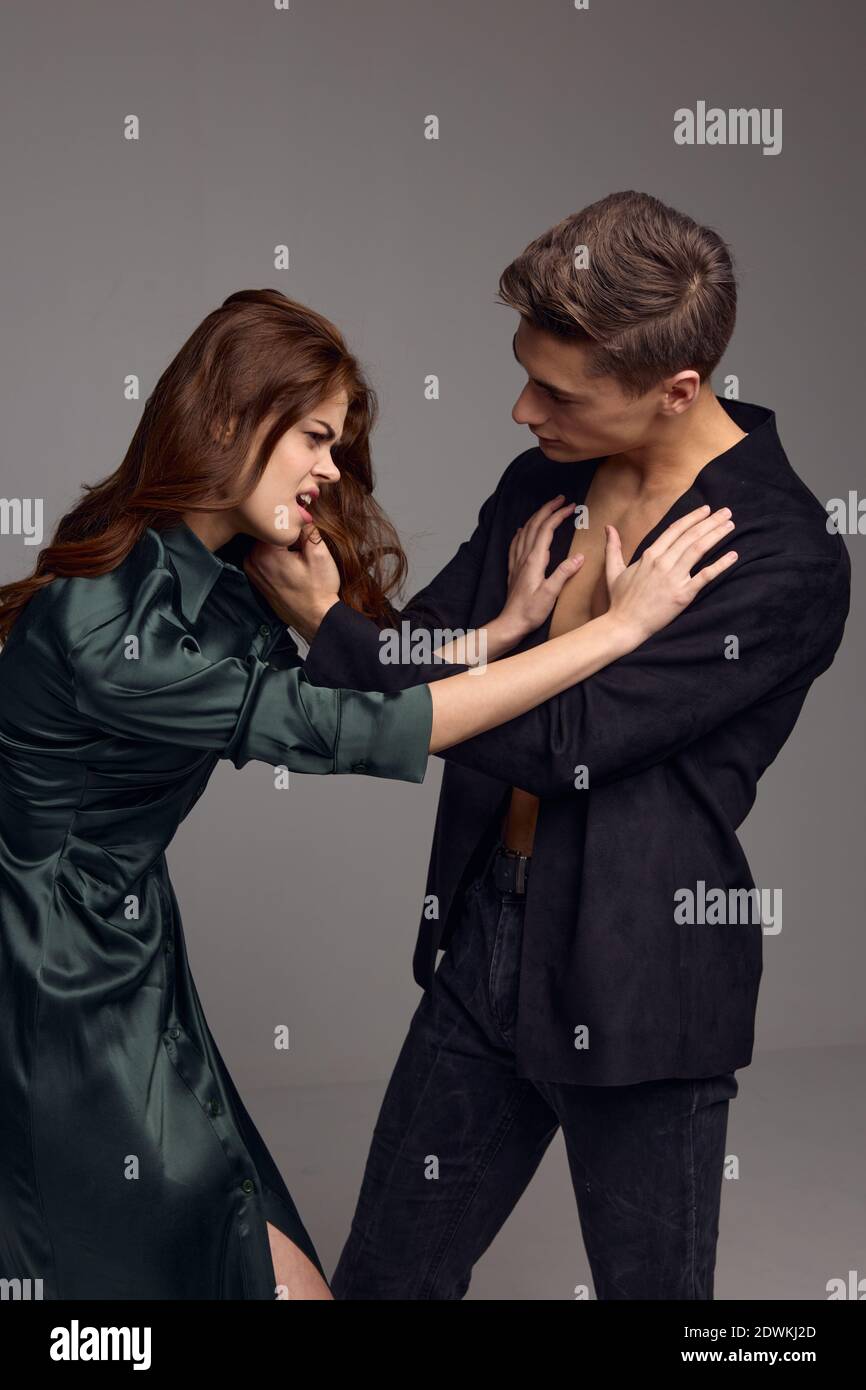 Aggressive woman pushes a man in the chest on a gray background Stock ...