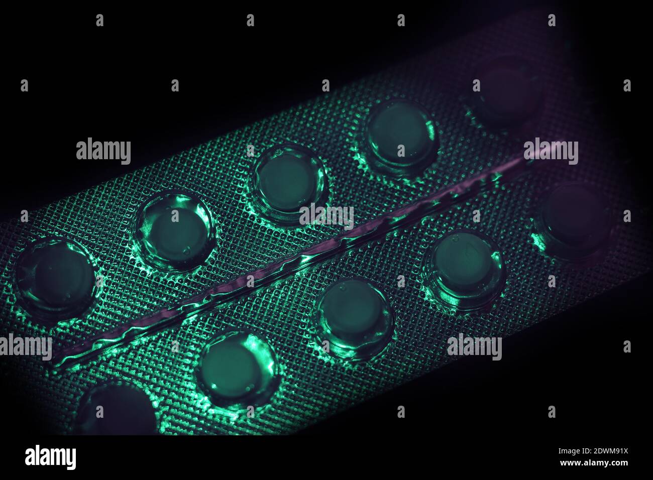 Pills or drugs in a package under neon light on a dark background ...
