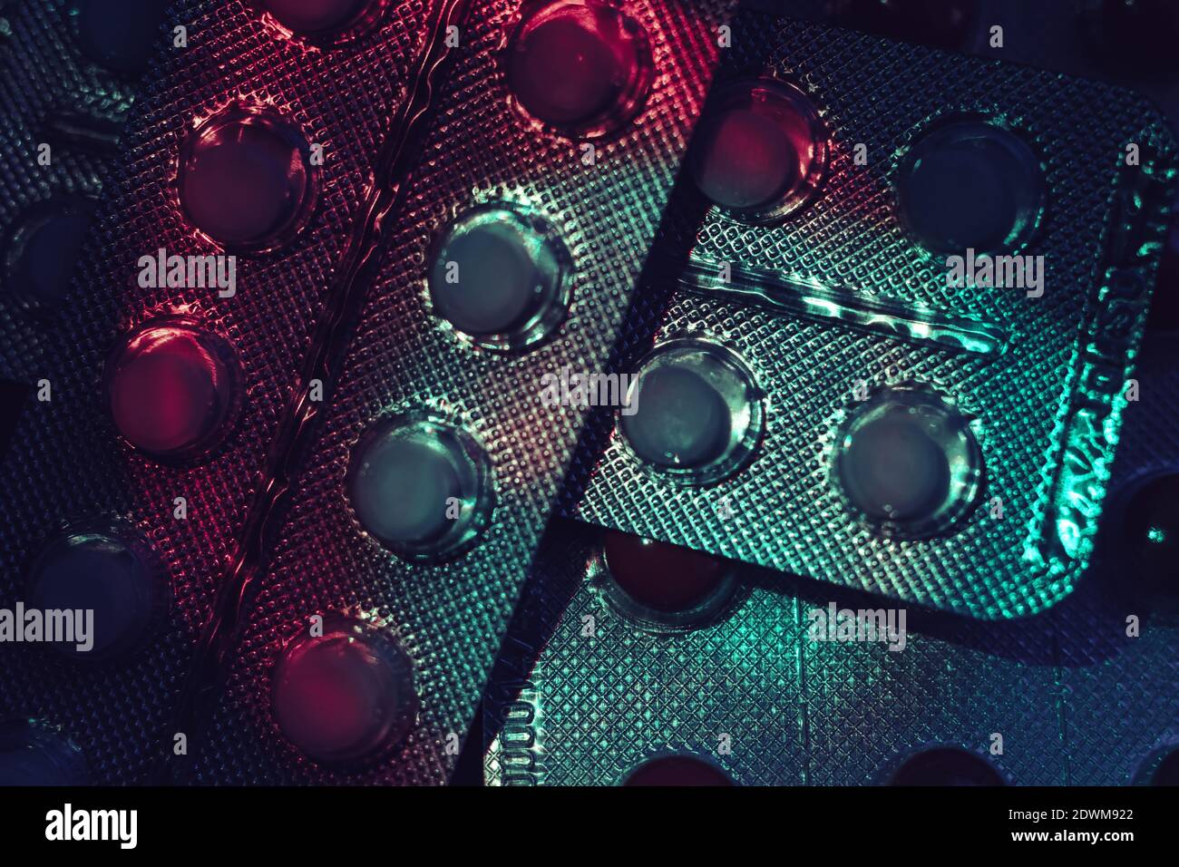 Pills or drugs in a package under neon light on a dark background ...