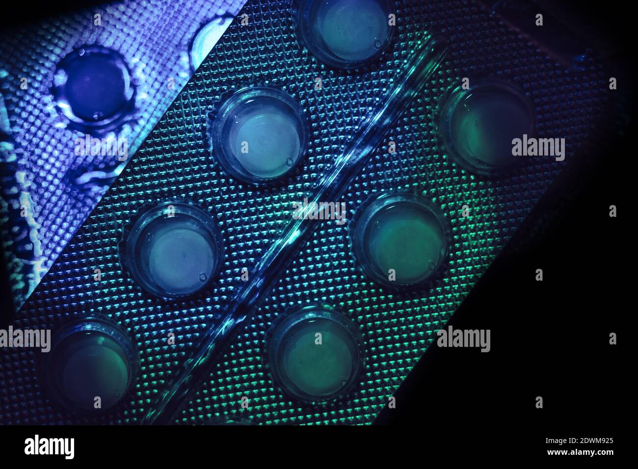 Pills or drugs in a package under neon light on a dark background ...