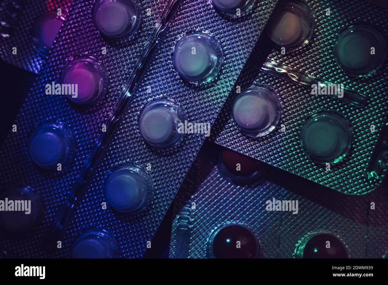 Pills or drugs in a package under neon light on a dark background ...