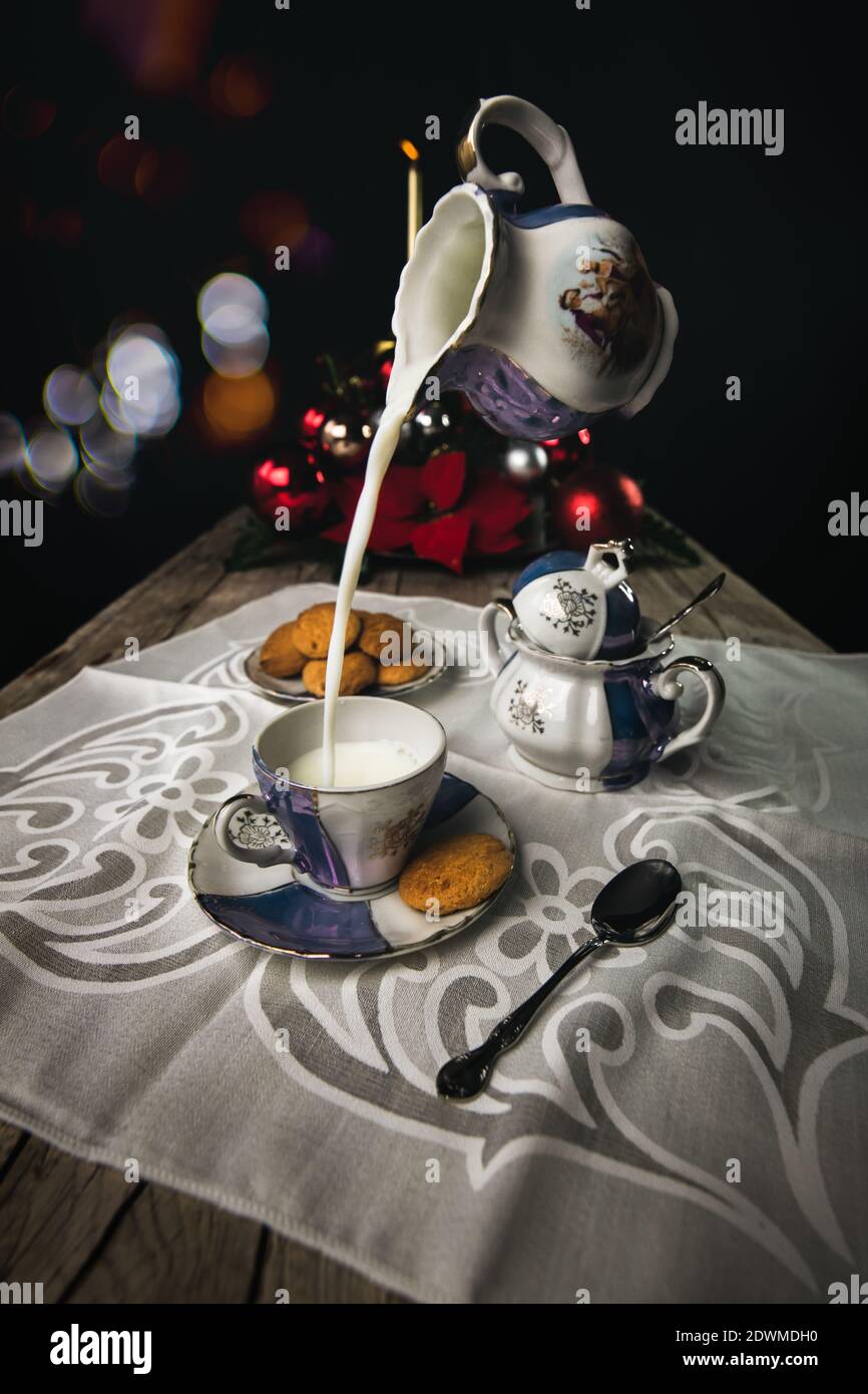 antique tea set with cookies and falling milk Stock Photo - Alamy