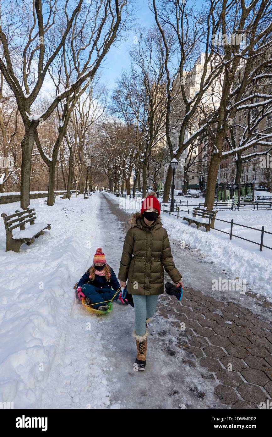 New York, USA, December 2020. Young girls wearing masks with their sled ...