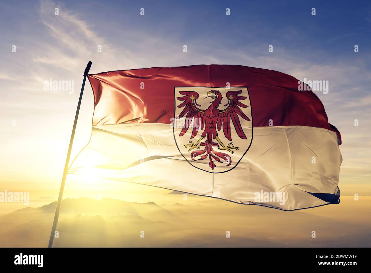 Brandenburg state of Germany flag waving on the top sunrise mist fog ...
