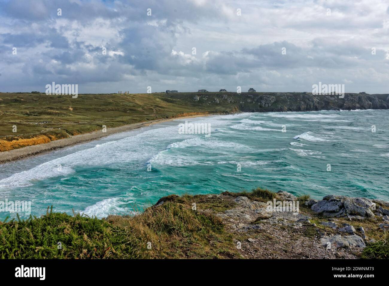 A rainy cloudscape over wavy seawater and grassy coastline Stock Photo ...