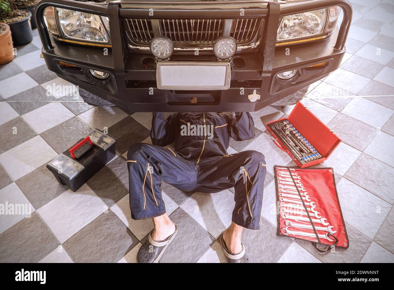 Car repair workers wearing blue uniforms are lying under the car to ...