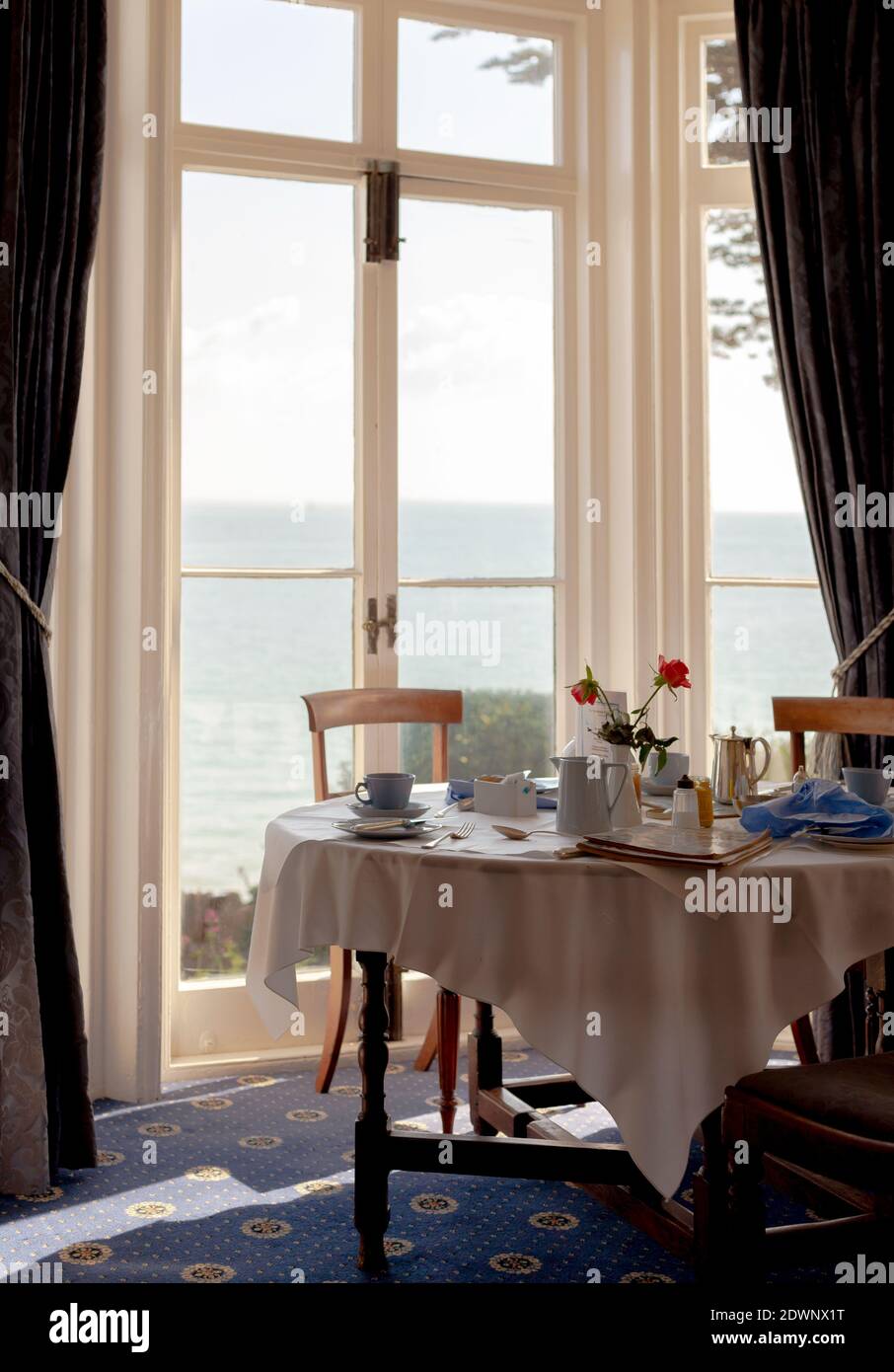 Morning sun illuminates a breakfast dining table set with tea cups ...