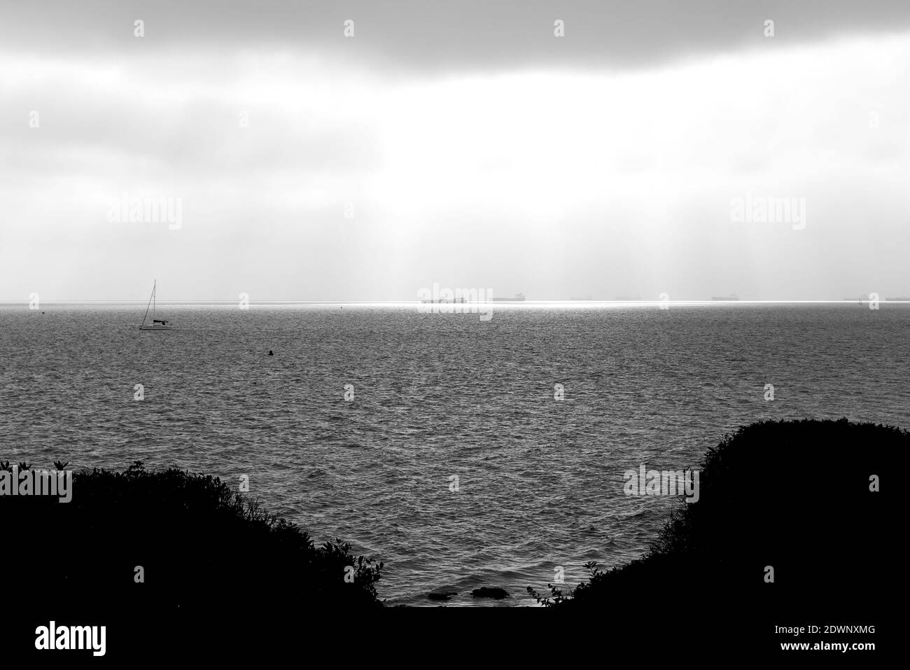 A ray of sun captures distant freight ships off the coast of Ryde, Isle ...