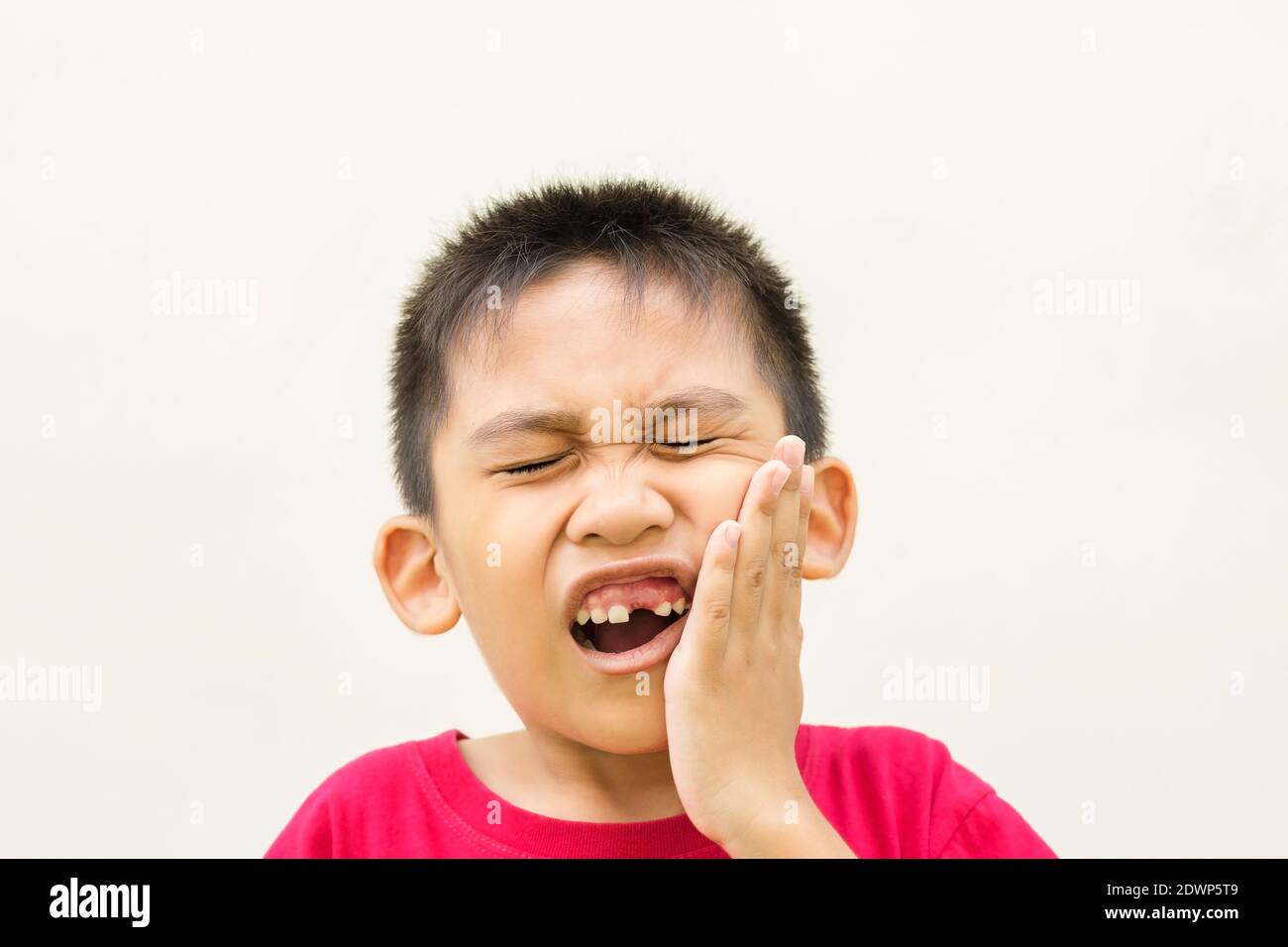 The boy is holding his hand on his cheek and red face with pain from ...