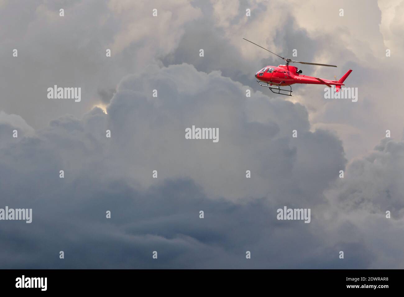 Red helicopter in flight in the cloudy sky Stock Photo - Alamy