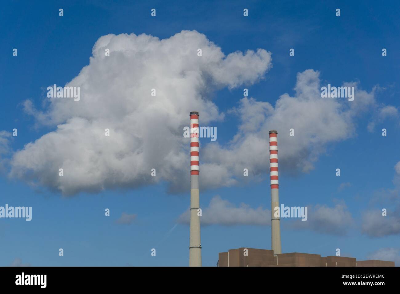 two tall smokestack chimneys of an industrial port factory under a blue ...