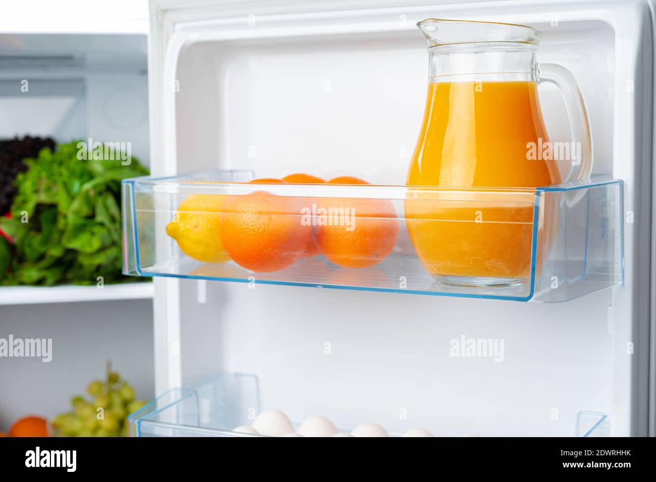 Glass pitcher of orange juice and fruits on fridge shelf Stock Photo ...