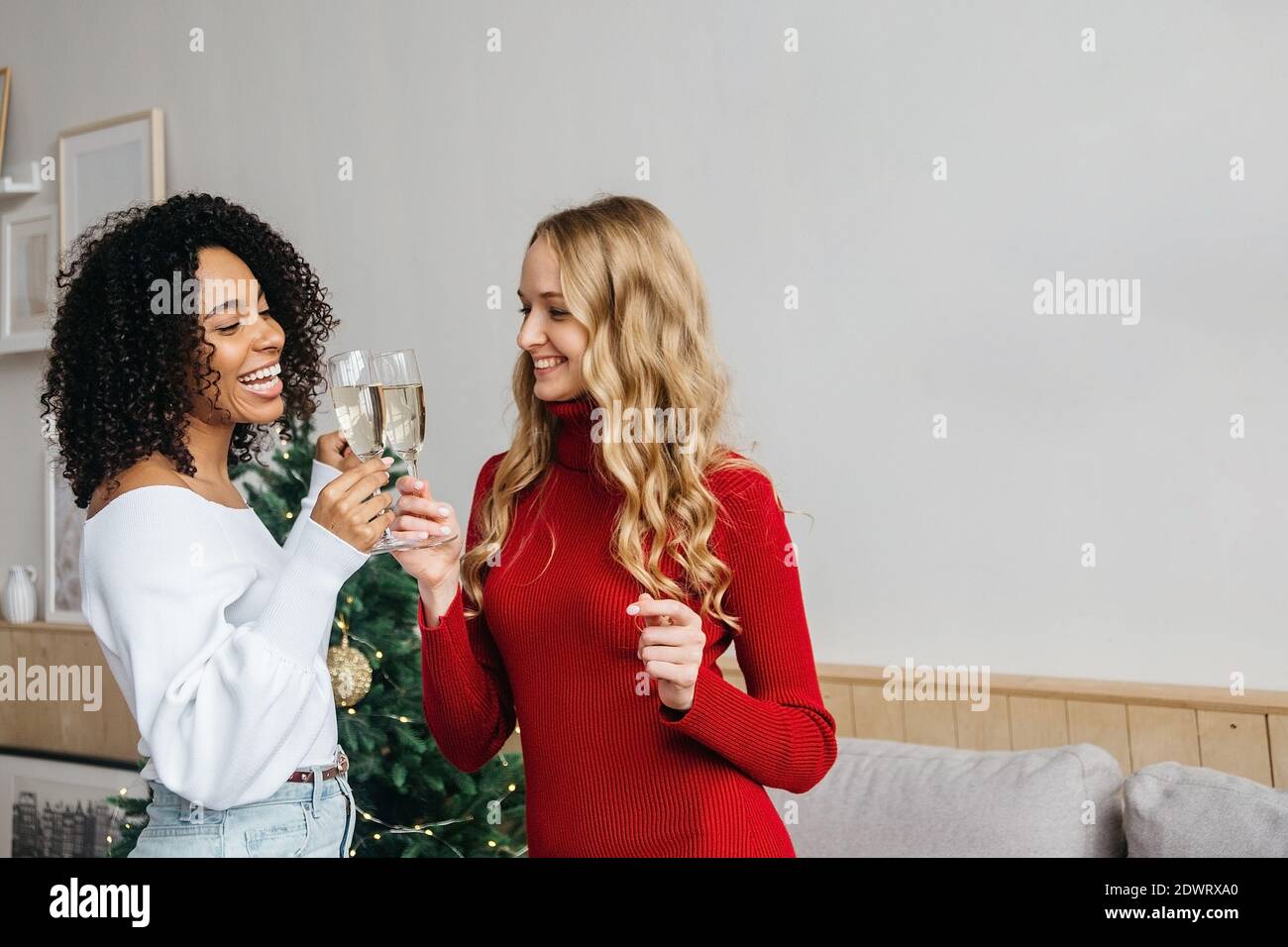 Smiling multiethnic young women friends cheers drink champagne enjoy ...