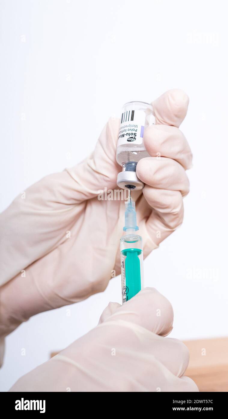 A selective focus shot of a hand holding an injection syringe with ...