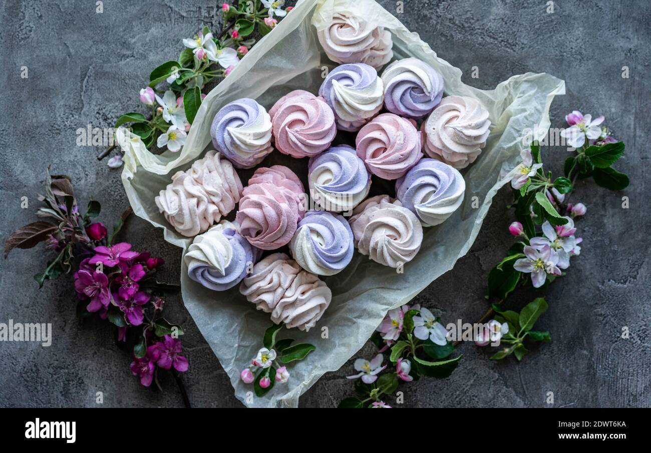 Top view of sweet marshmallows on craft paper framed by spring flowers ...