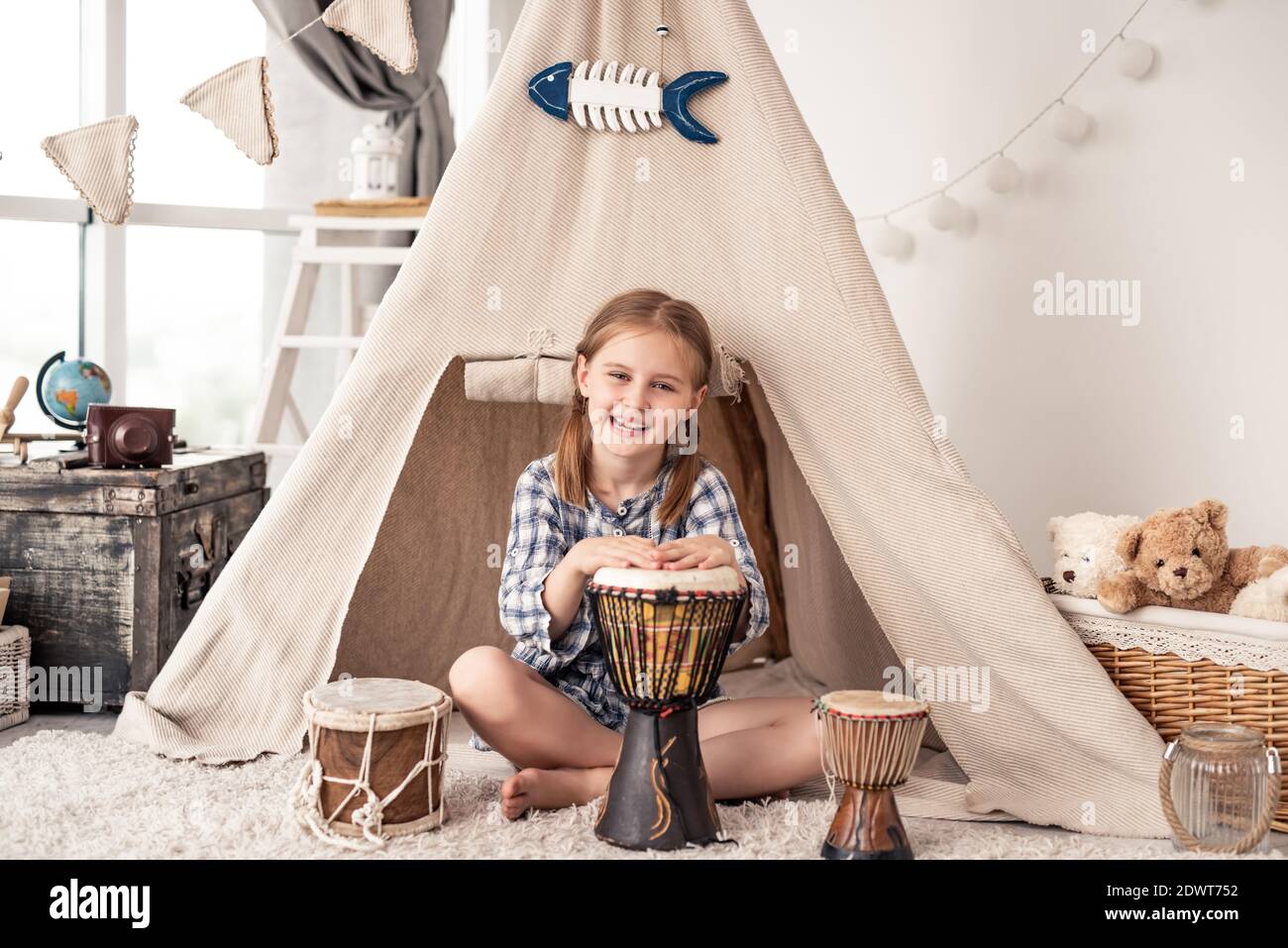 Little girl playing on traditional african djembe drums sitting in ...