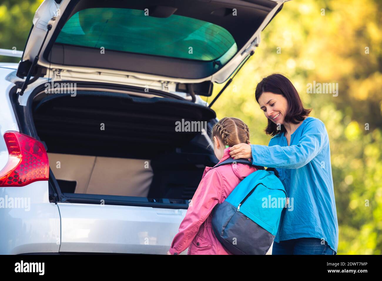 Mother and daughter before lessons at school near open car trunk ...
