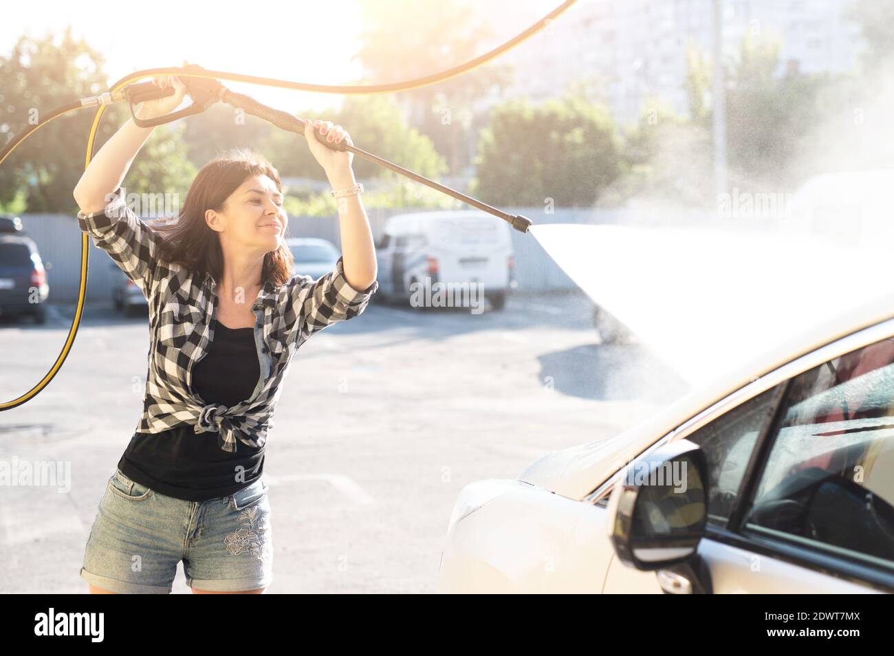 Girl cleaning car window with jet water during car washing Stock Photo ...
