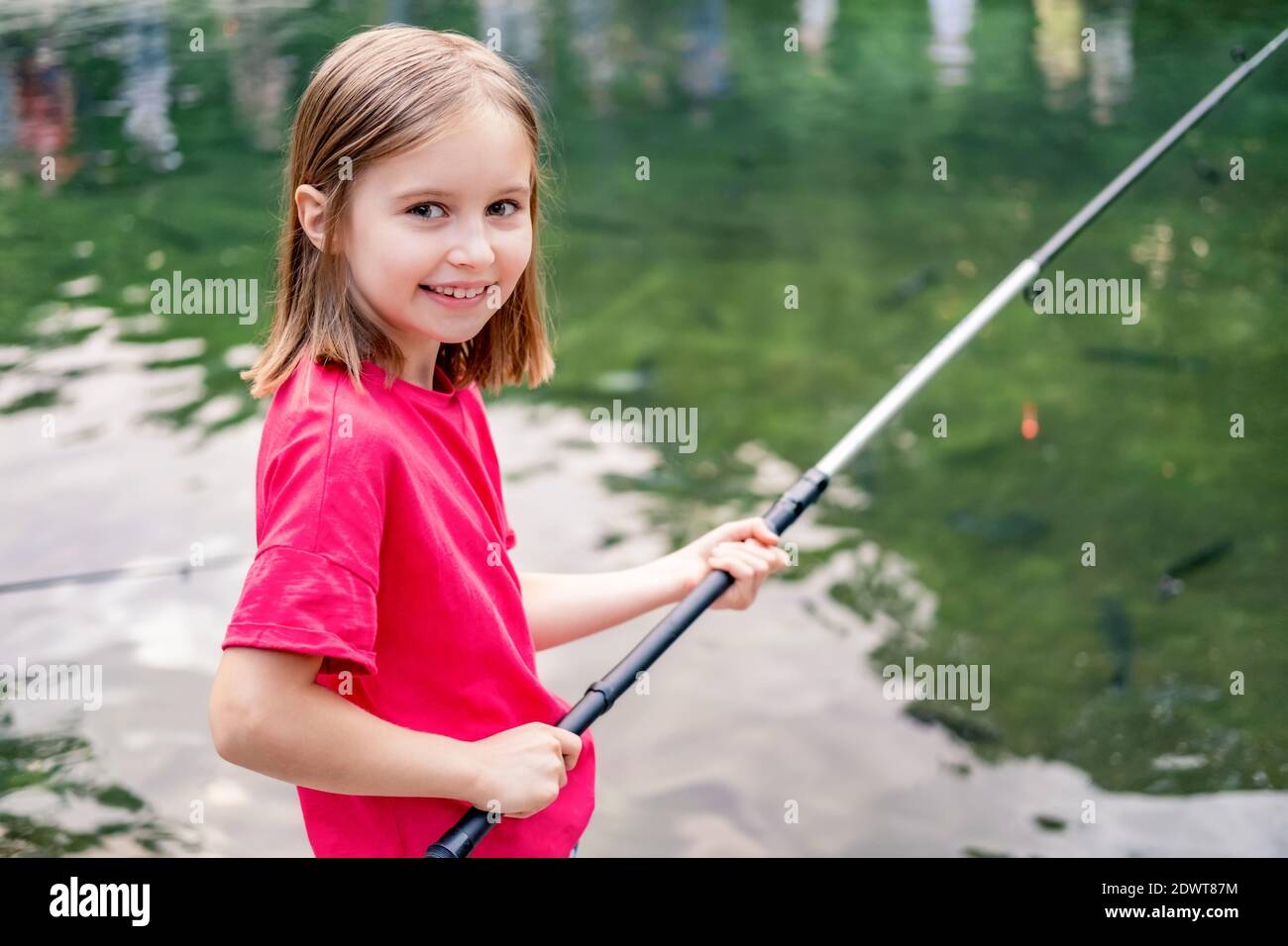 Little girl holding fishing rod on pond background Stock Photo - Alamy