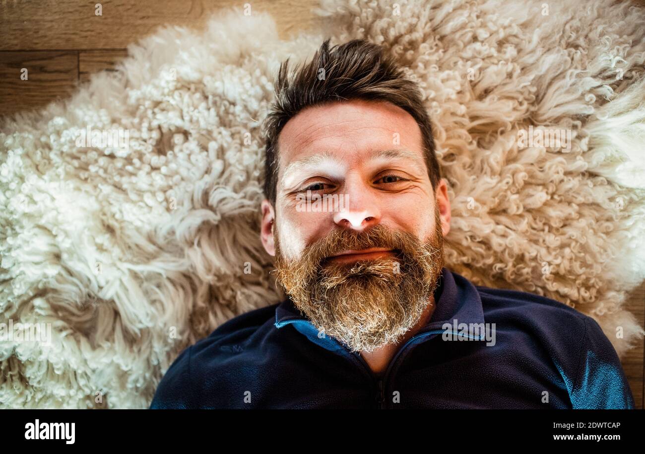 portrait of happy relaxed man laying on sheepskin rug Stock Photo - Alamy