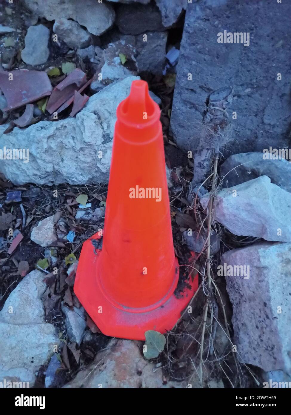 a vertical shot of plastic garbage left on the ground among stones and ...