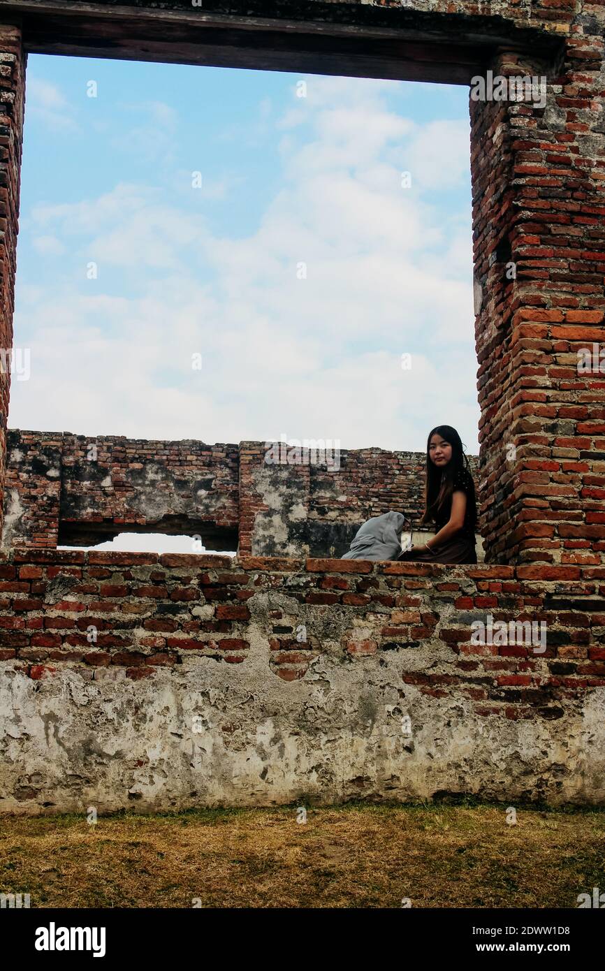 Portrait Of Woman Sitting On Brick Wall Stock Photo - Alamy