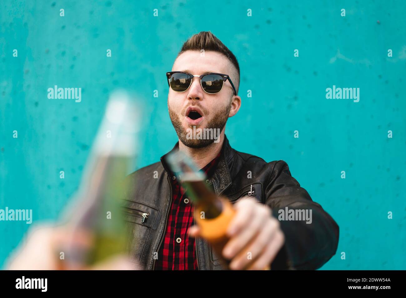 Bearded cool man toasting beer with best friend outdoor against a blue ...