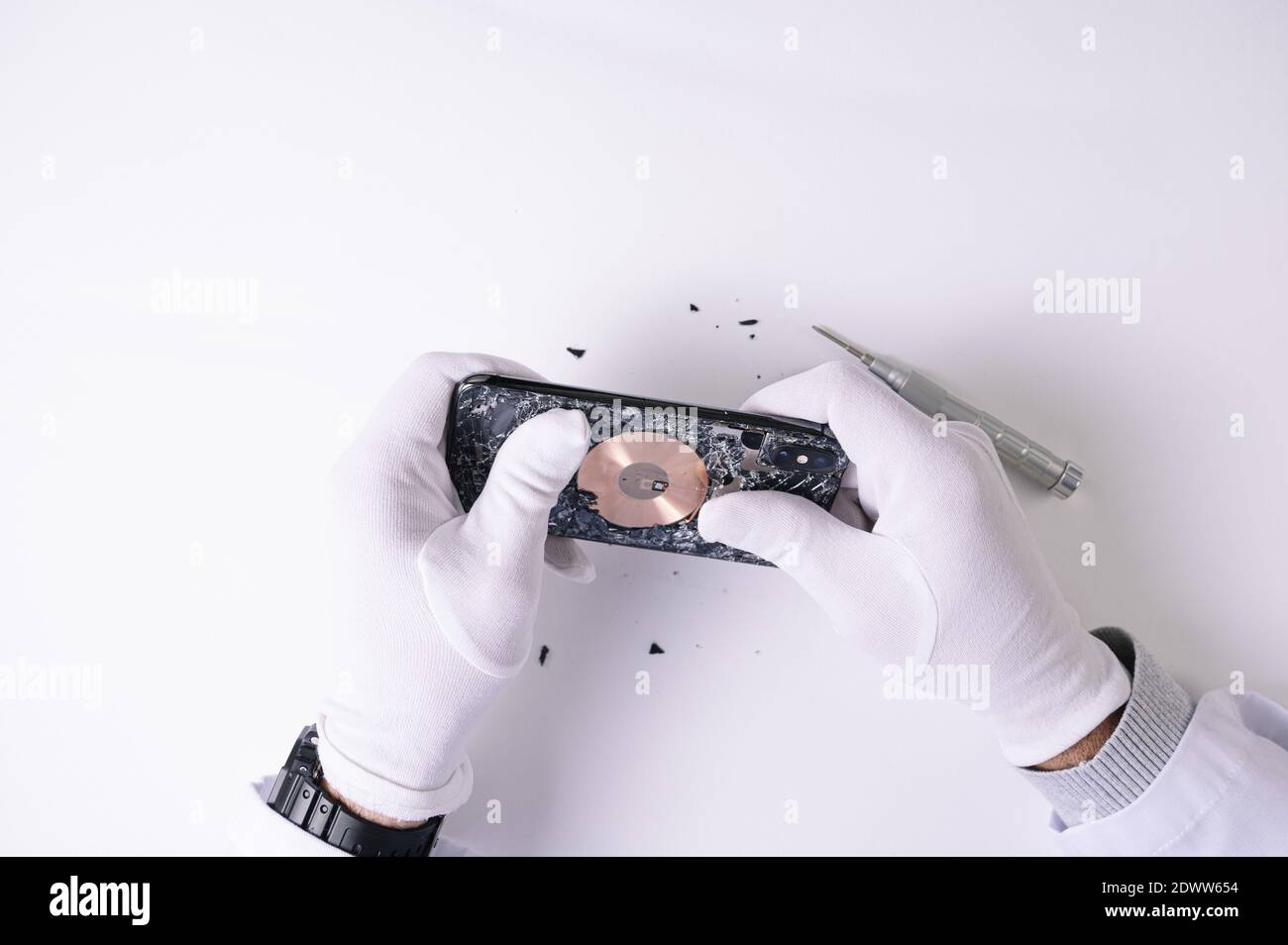A technician with rubber gloves repairing broken smartphone with tools ...