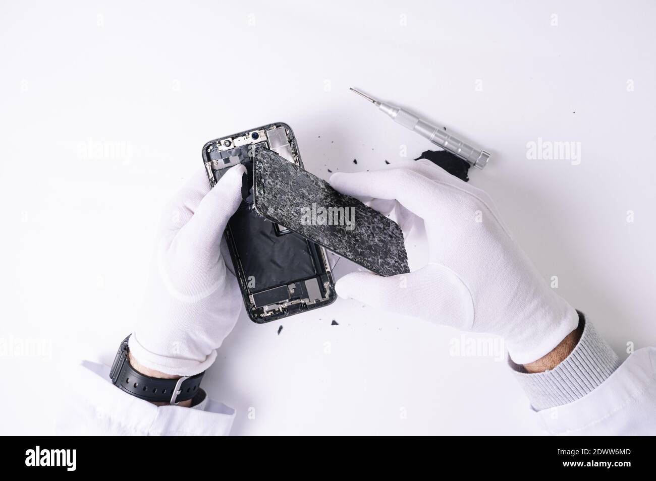 A technician with rubber gloves repairing broken smartphone with tools ...
