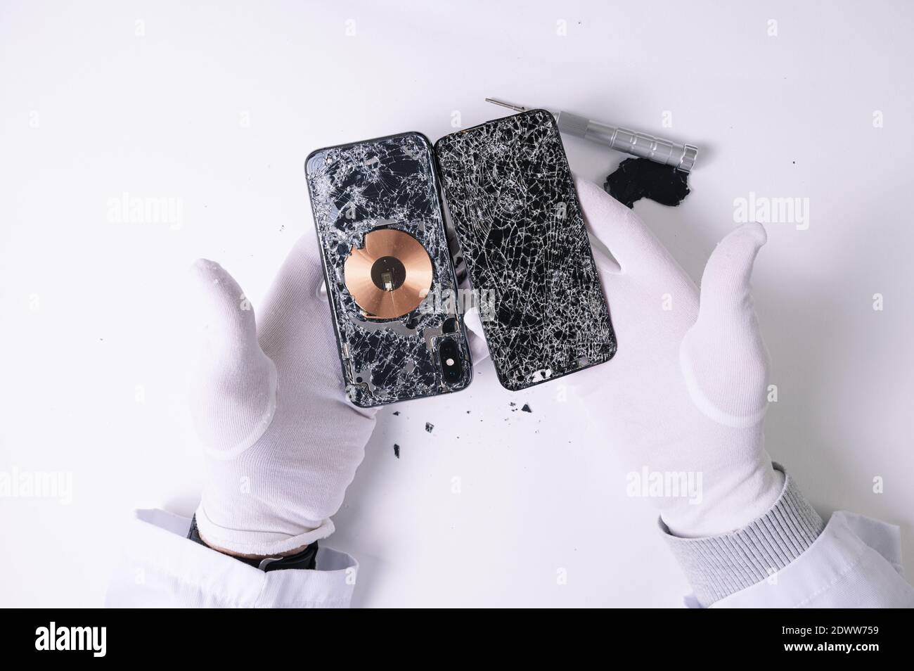 A technician with rubber gloves repairing broken smartphone with tools ...