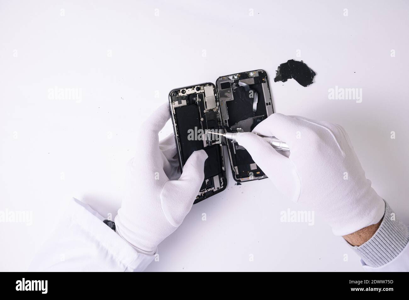 A technician with rubber gloves repairing broken smartphone with tools ...