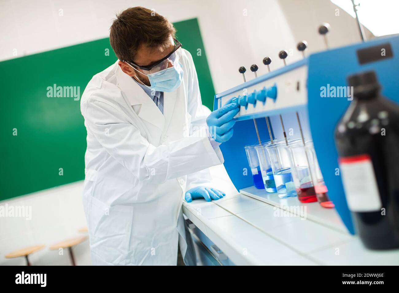 Young researcher with protective goggles checking test tubes in ...