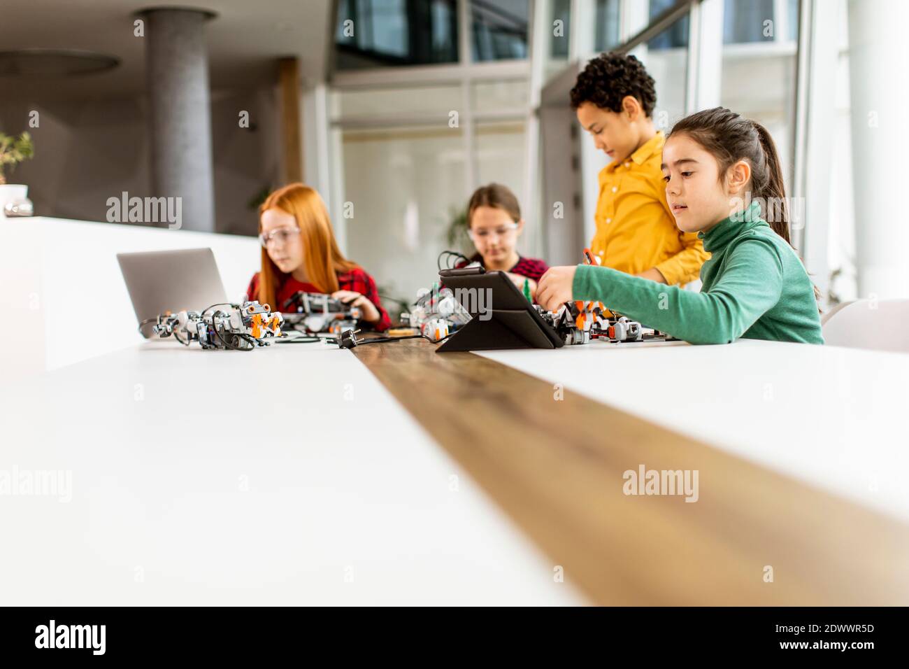 Group of happy kids programming electric toys and robots at robotics ...