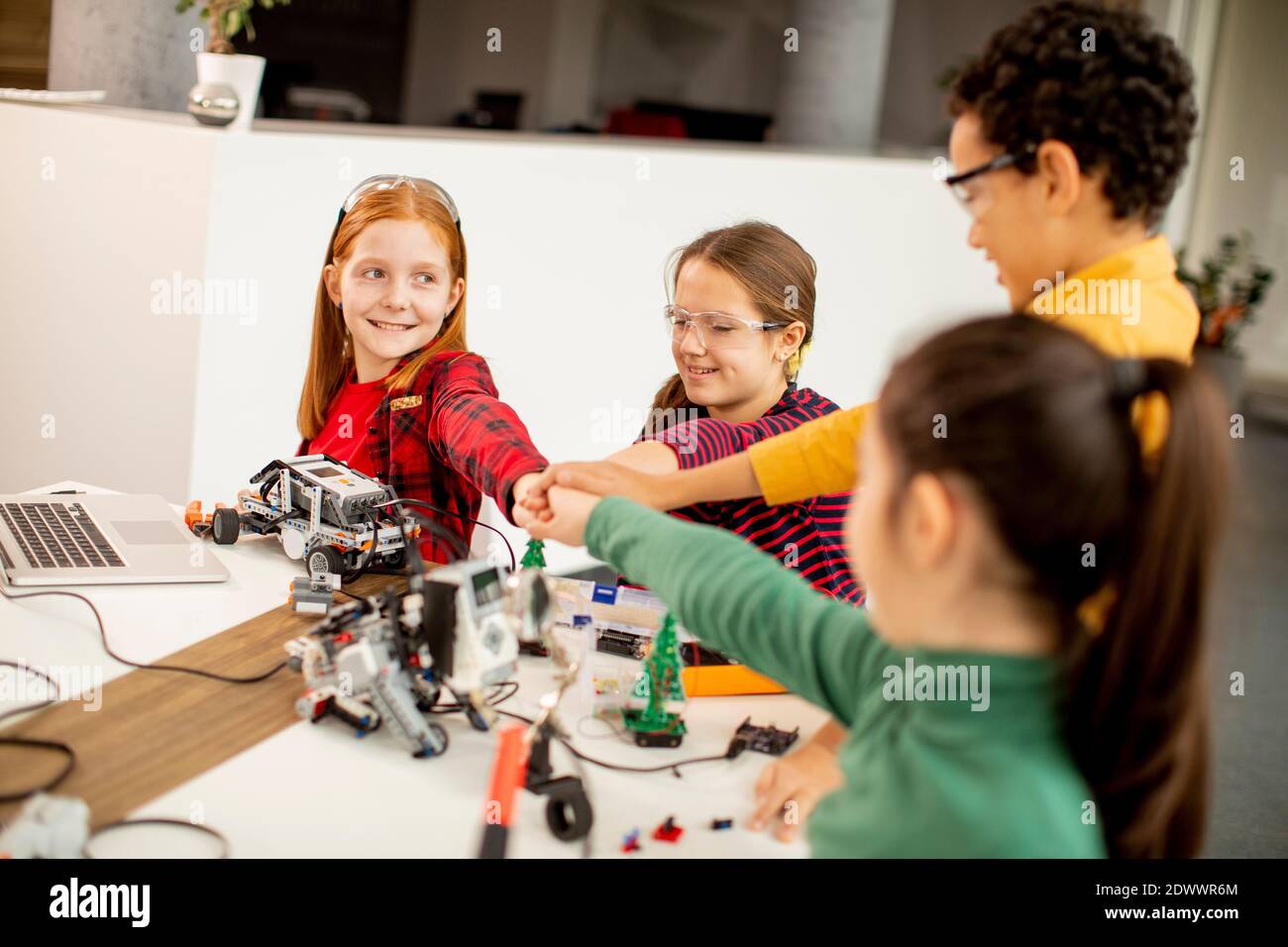 Group of happy kids programming electric toys and robots at robotics ...