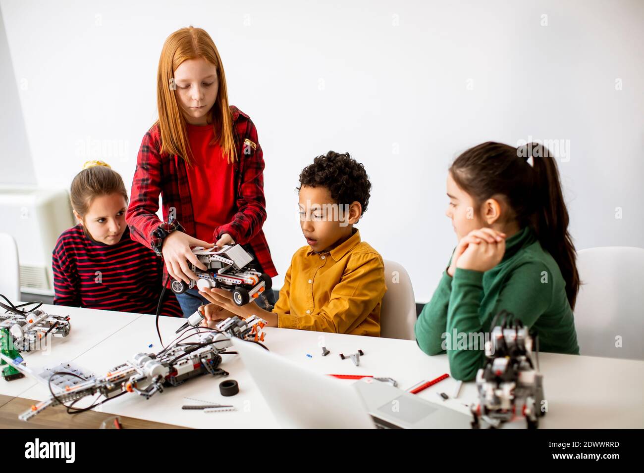 Group of happy kids programming electric toys and robots at robotics ...