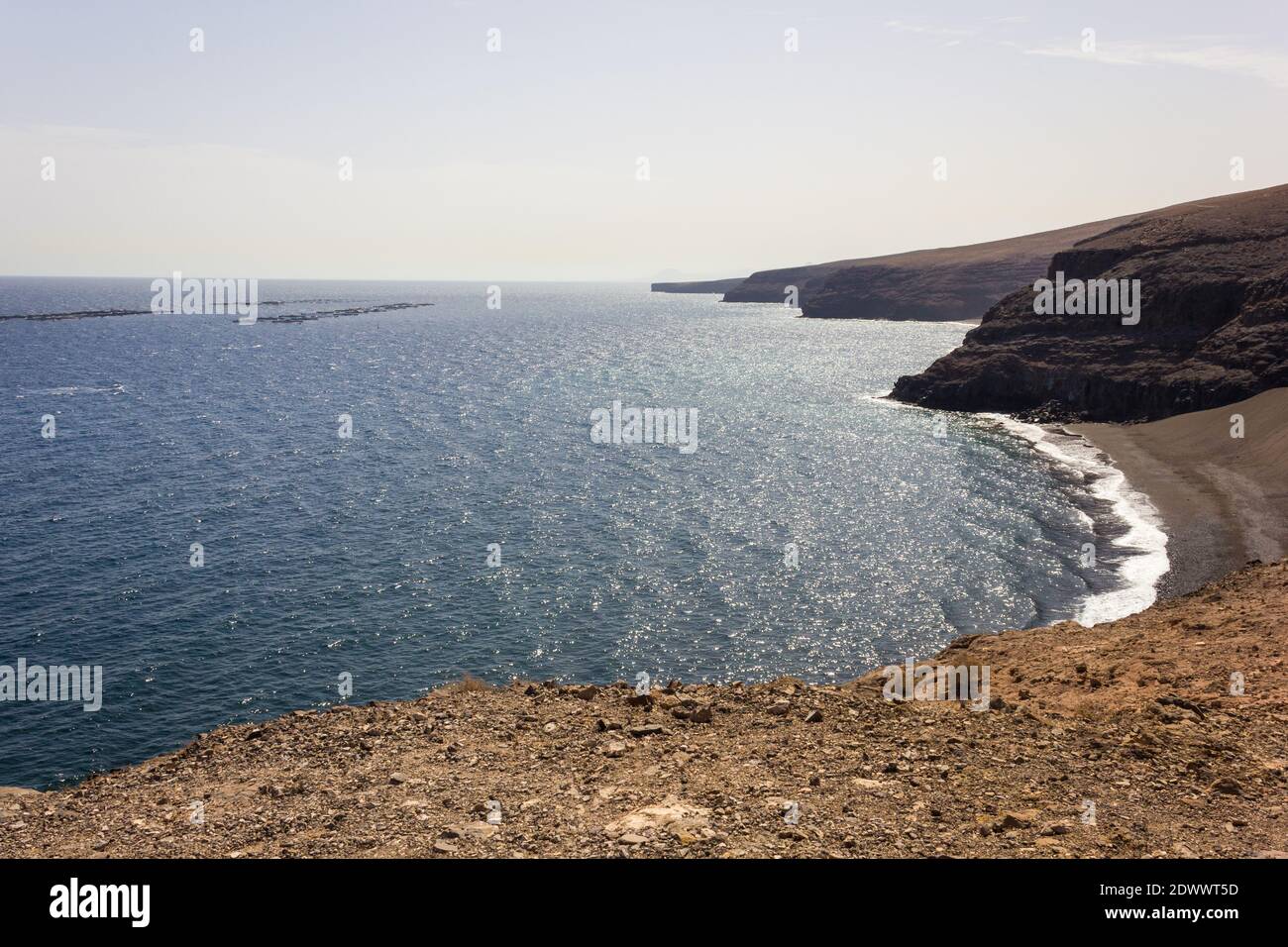 Lanzarote volcanic coast with fish farm floating on blue ocean offshore ...