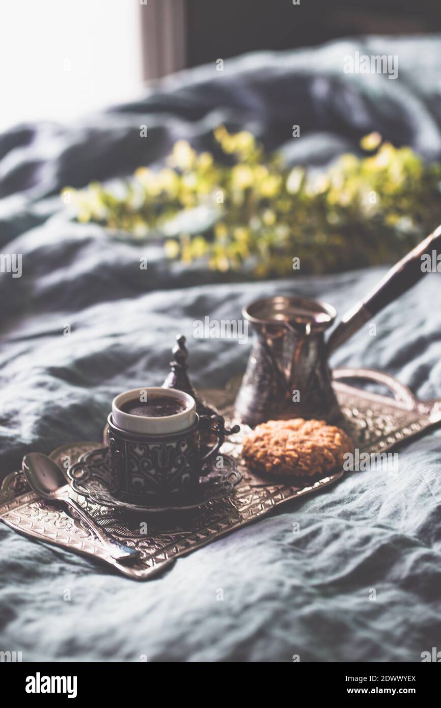 Morning coffee on vintage metal tray in bed with grey sheet and pillows ...