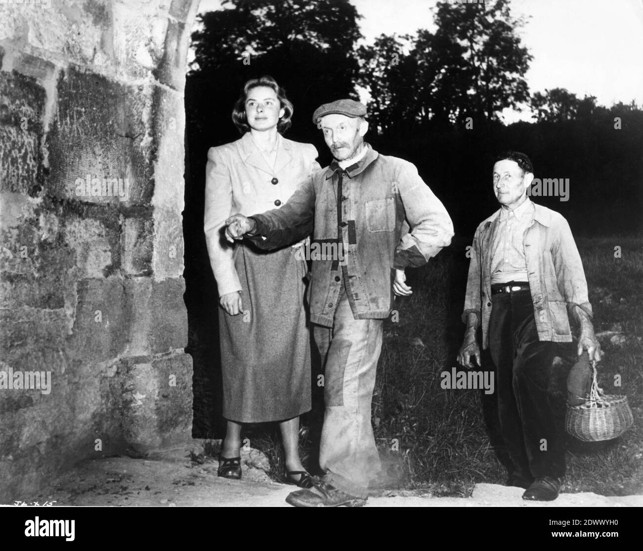 INGRID BERGMAN being escorted by two villagers through the ruins of the ...