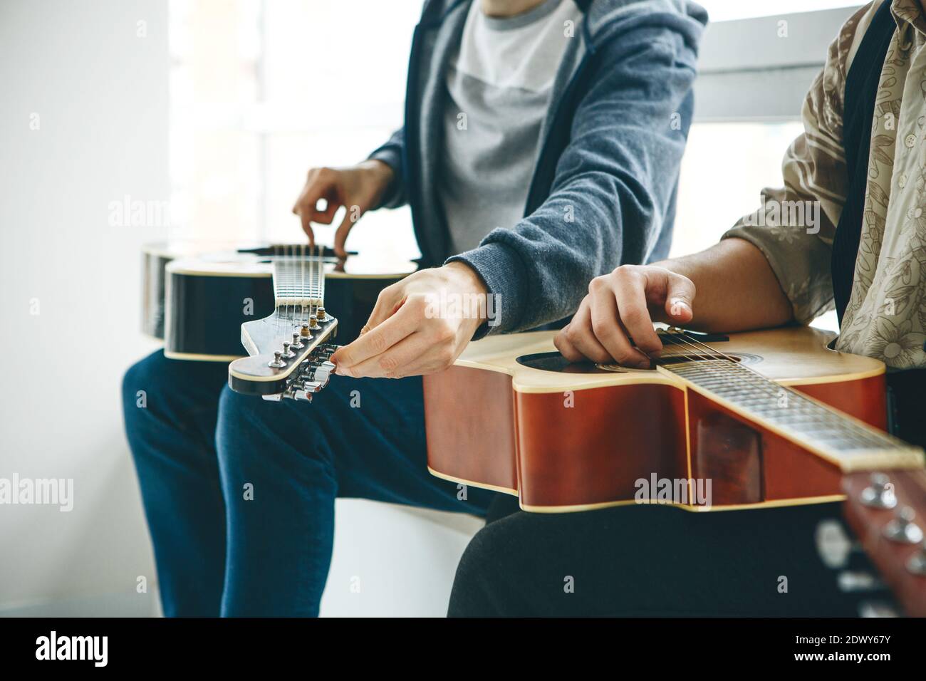 Learning to play the guitar. The teacher helps the student tune the ...