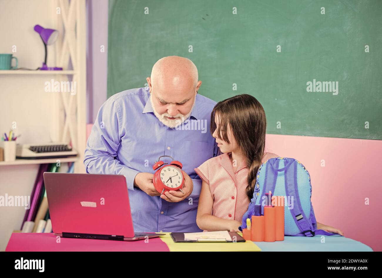 Children education. mature teacher help pupil with clock. small girl ...