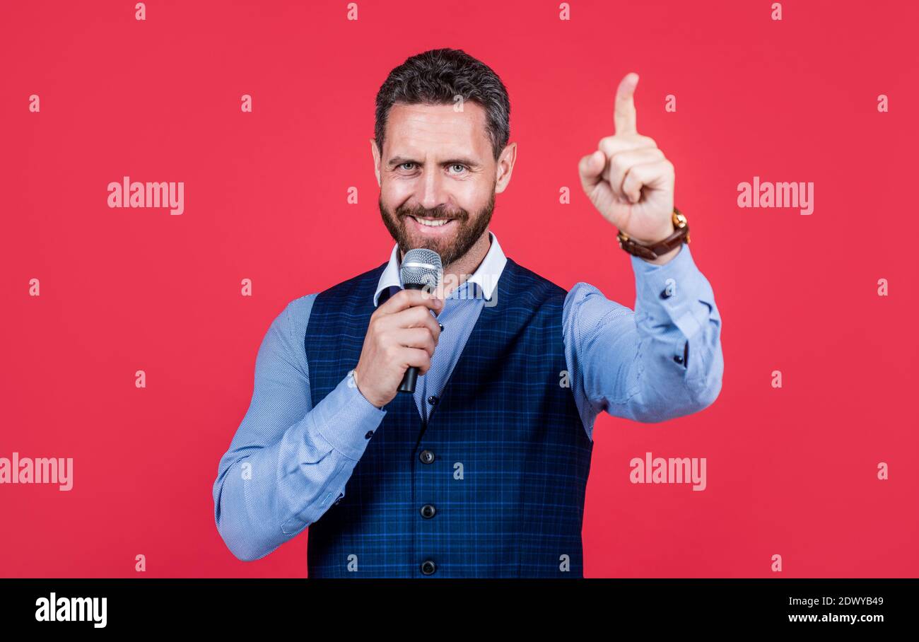Talk show host. Happy speaker speak into microphone keeping finger ...